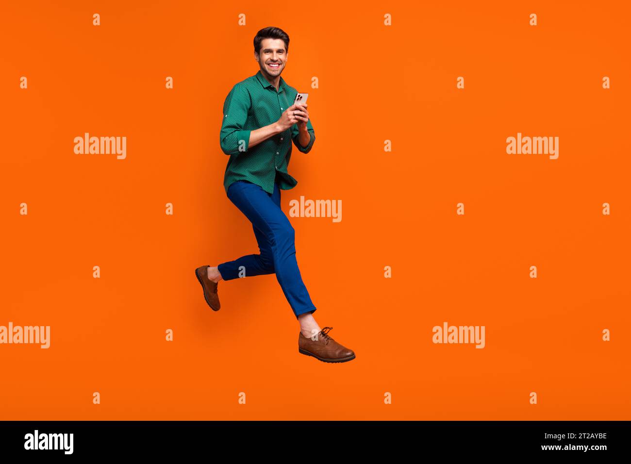 Full body cadre of young funky businessman running with smartphone ...