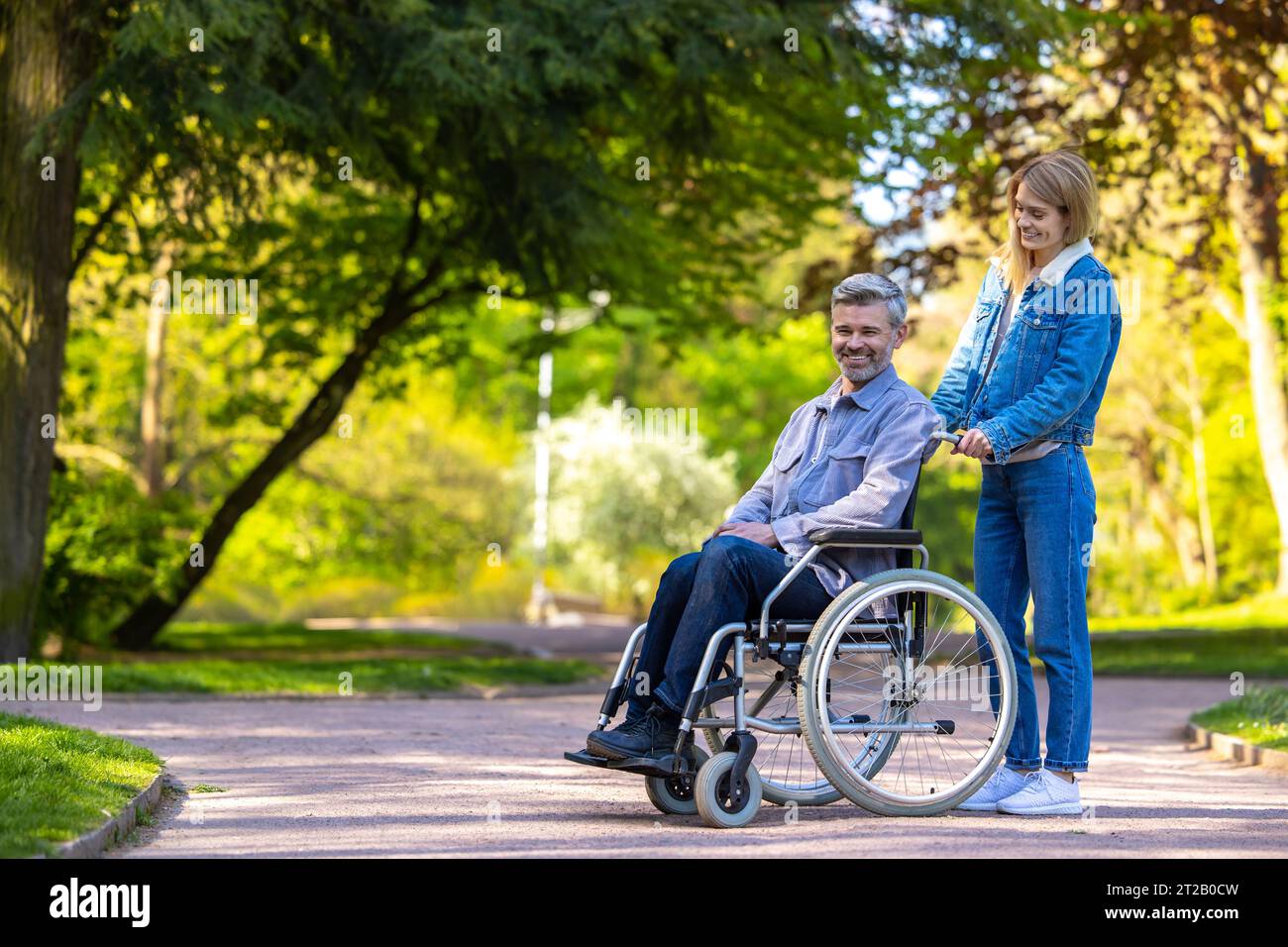 Man on a wheelchair having a walk in the park with his wife Stock Photo ...