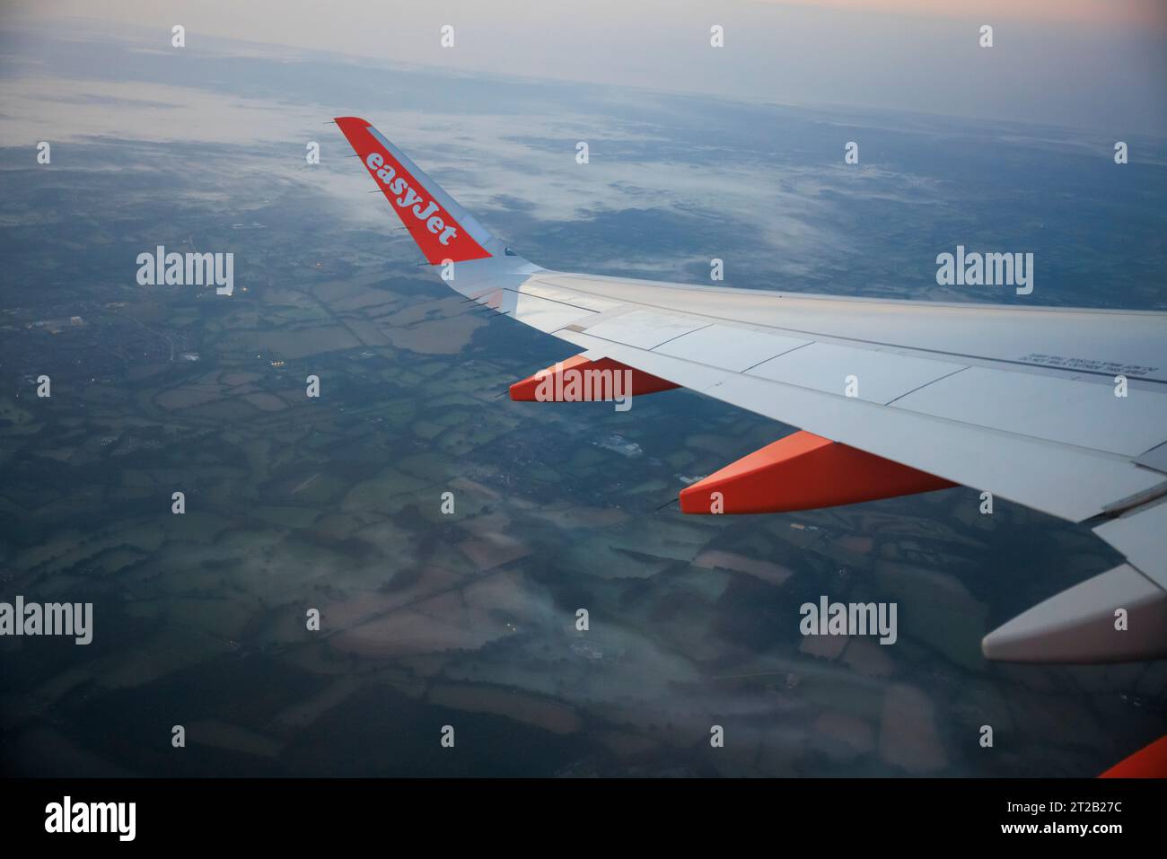 The wing tip of easyJet plane over a view of misty fields in the early ...