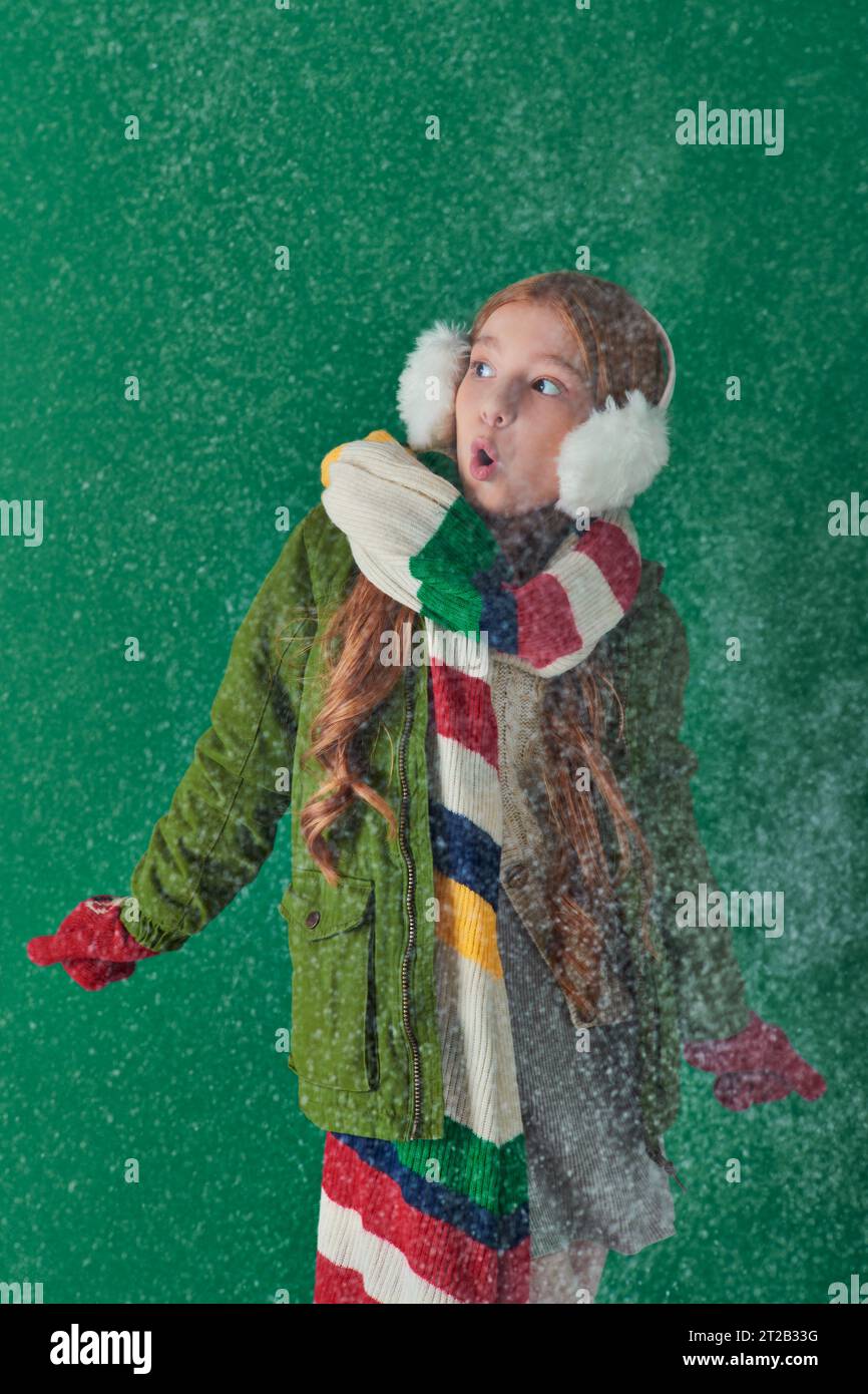 shocked girl in ear muffs, striped scarf and winter attire standing ...