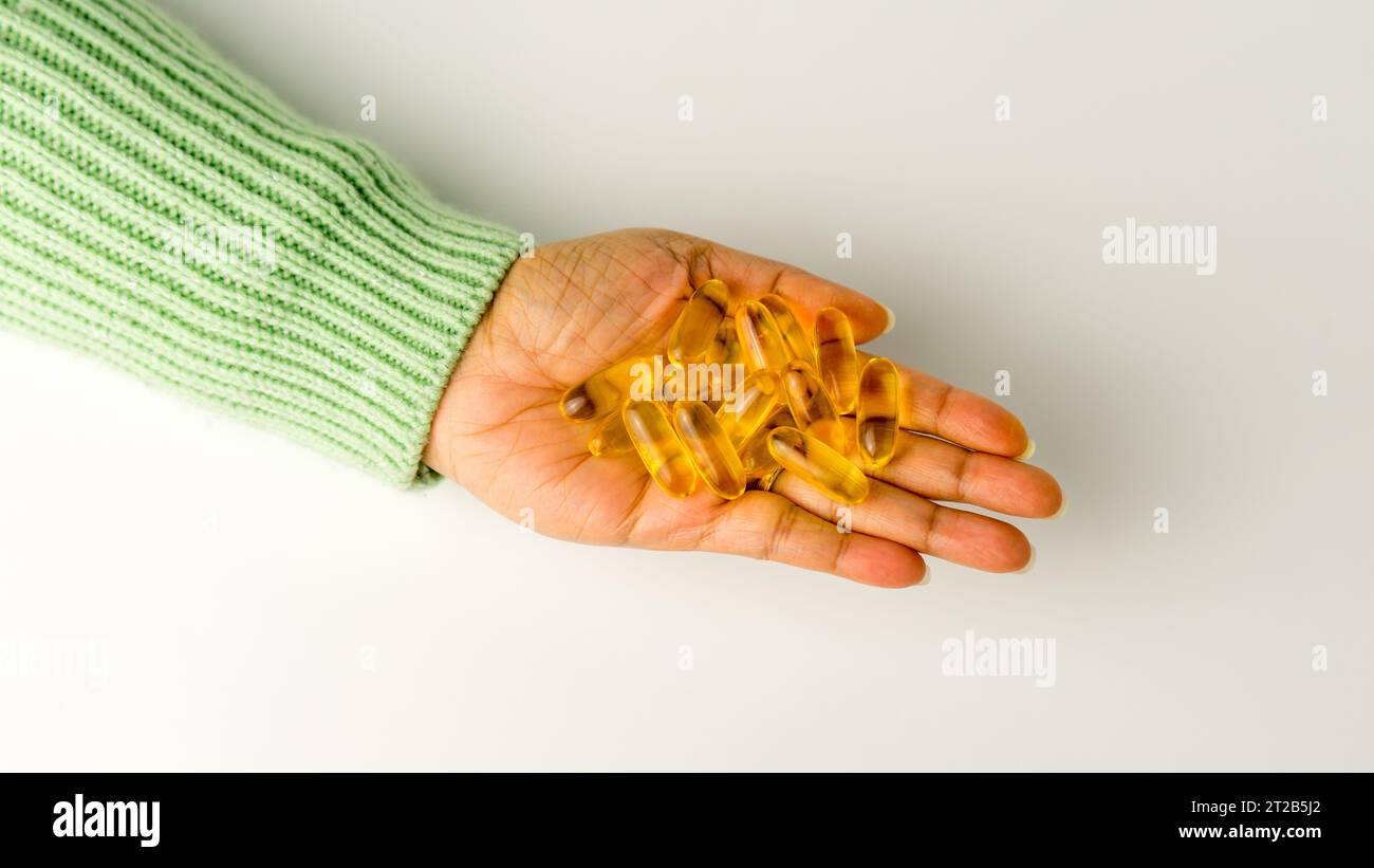 Handful of Omega-3-rich wild salmon and fish oil capsules presented on ...
