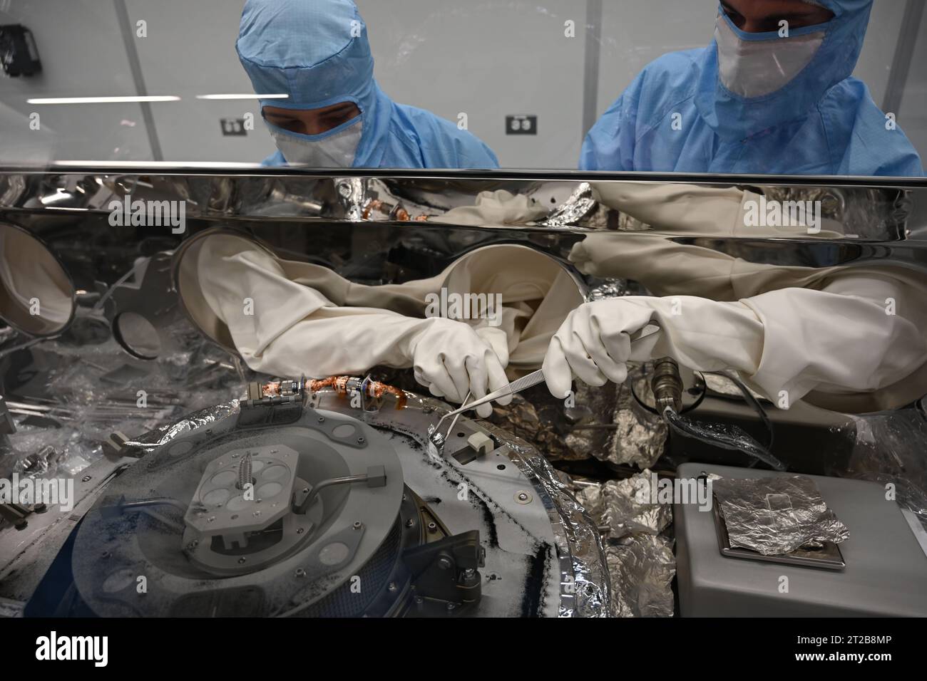 . Astromaterials processors Mari Montoya, left, and Curtis Calva, right, use tools to collect ...