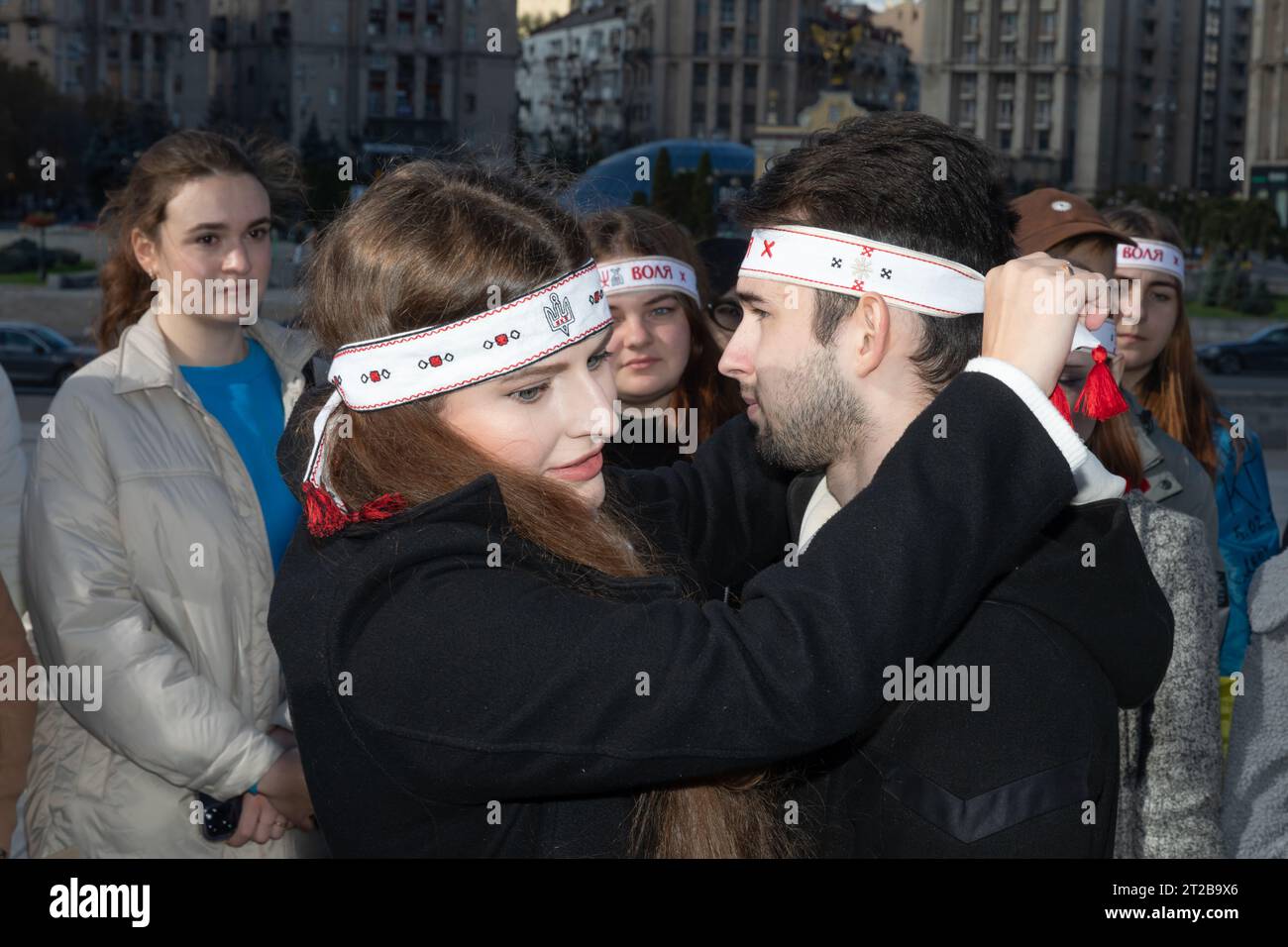 A student helps a colleague to tie a headband with the words Volya ...
