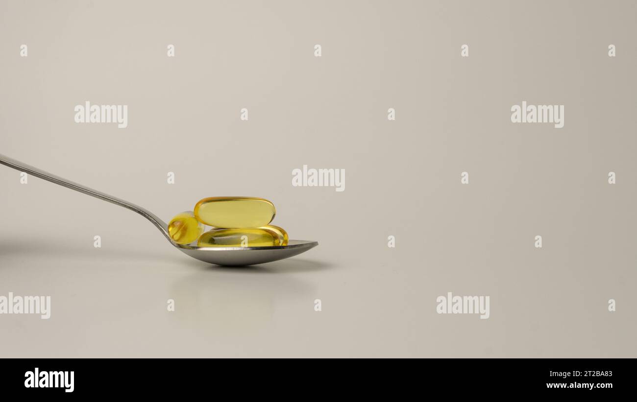 A spoon full of Omega-3-rich wild salmon and fish oil capsules ...