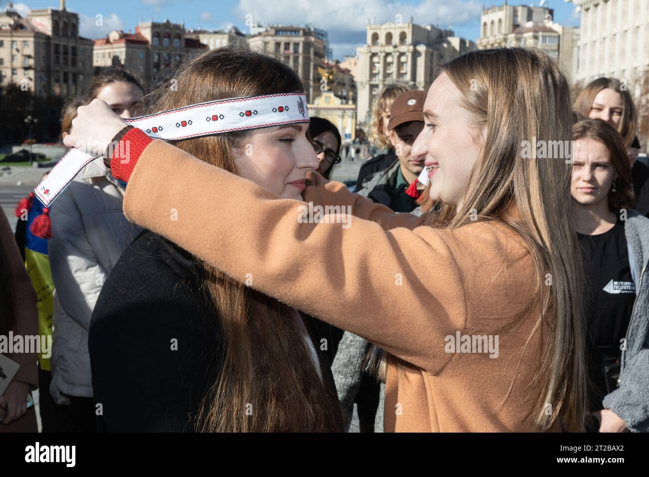 Students help each other to tie a headband with the words Volya ...