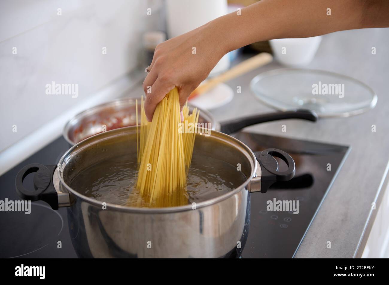 Close-up of chef hand dipping Italian pasta, wholegrain spaghetti ...