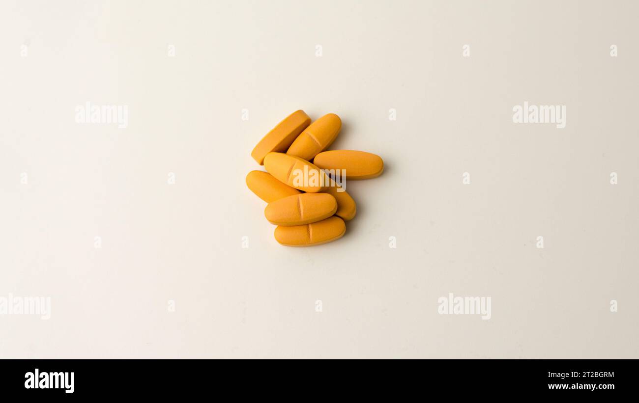 Multivitamin supplement pills set against a neutral off-white backdrop ...