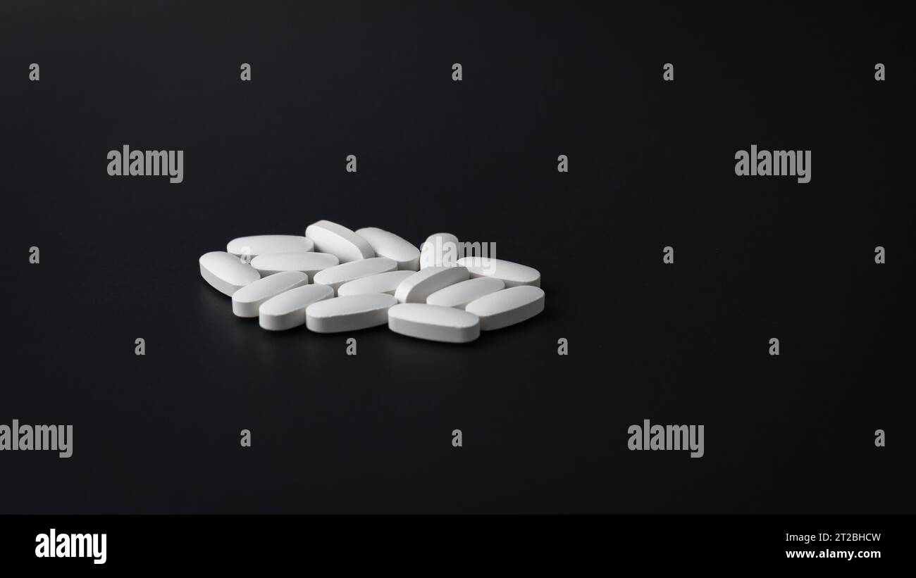 Calcium supplement pills on black background Stock Photo - Alamy