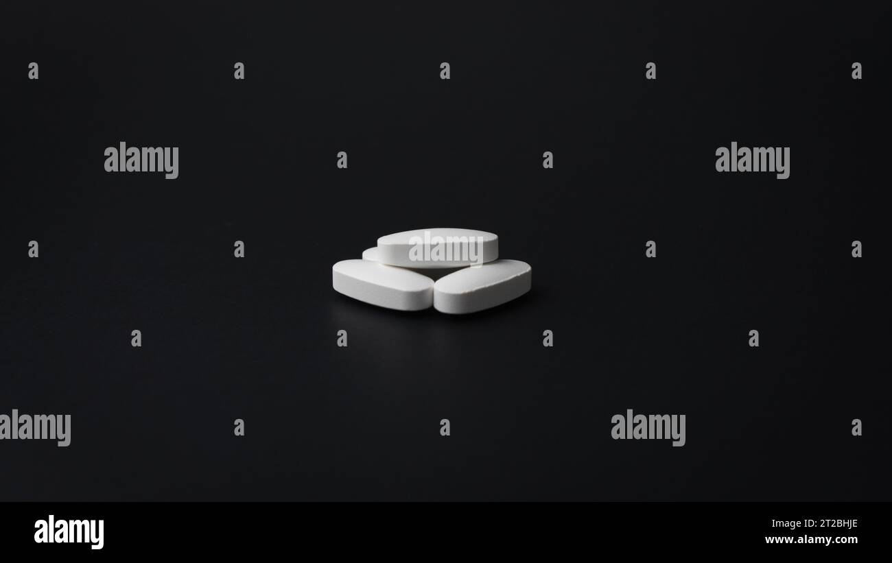 Calcium supplement pills on black background Stock Photo - Alamy