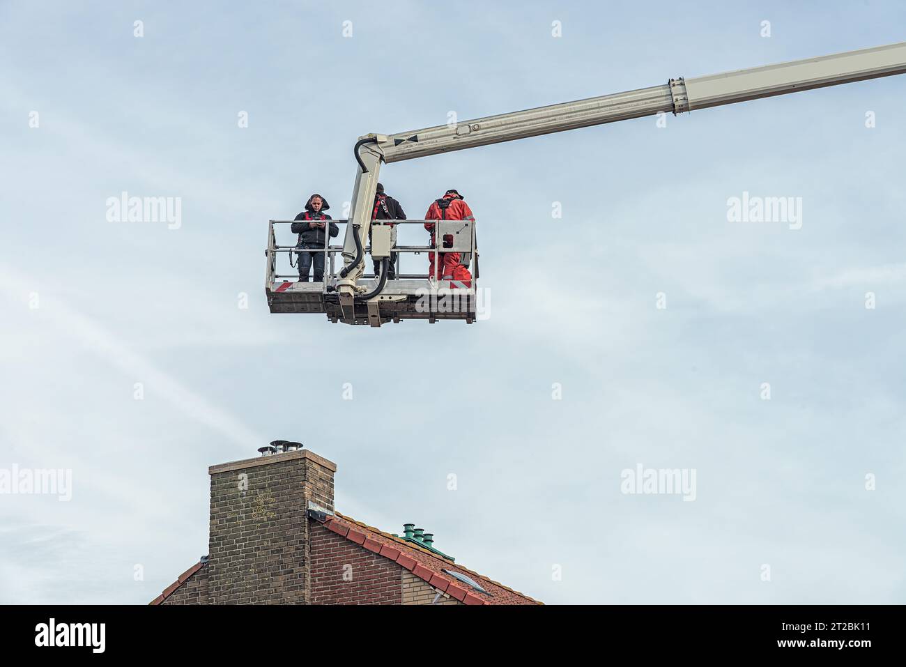 three people stand on the platform of an aerial platform above an ...