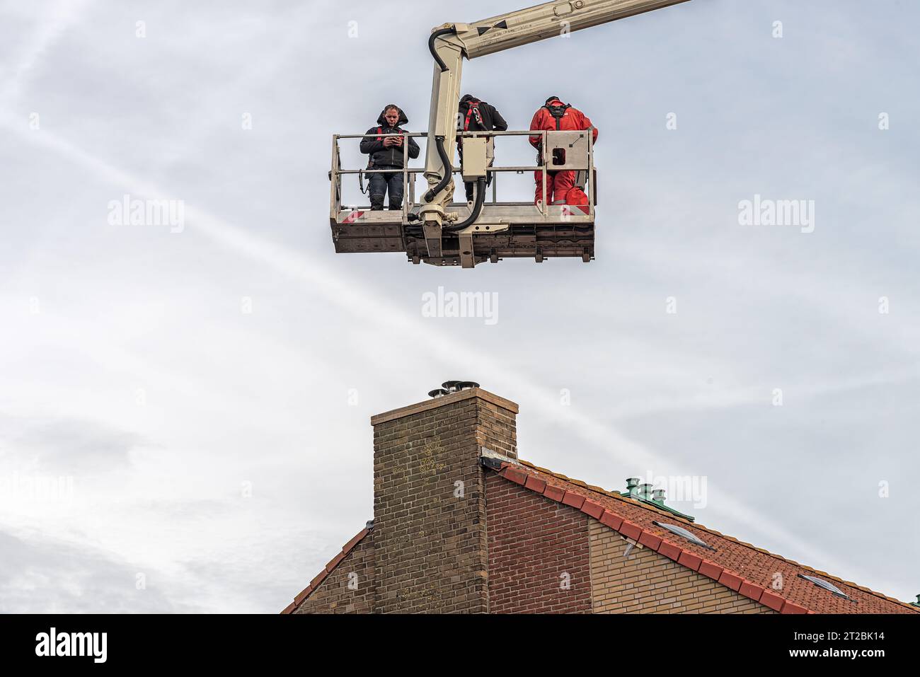 three people stand on the platform of an aerial platform above an ...