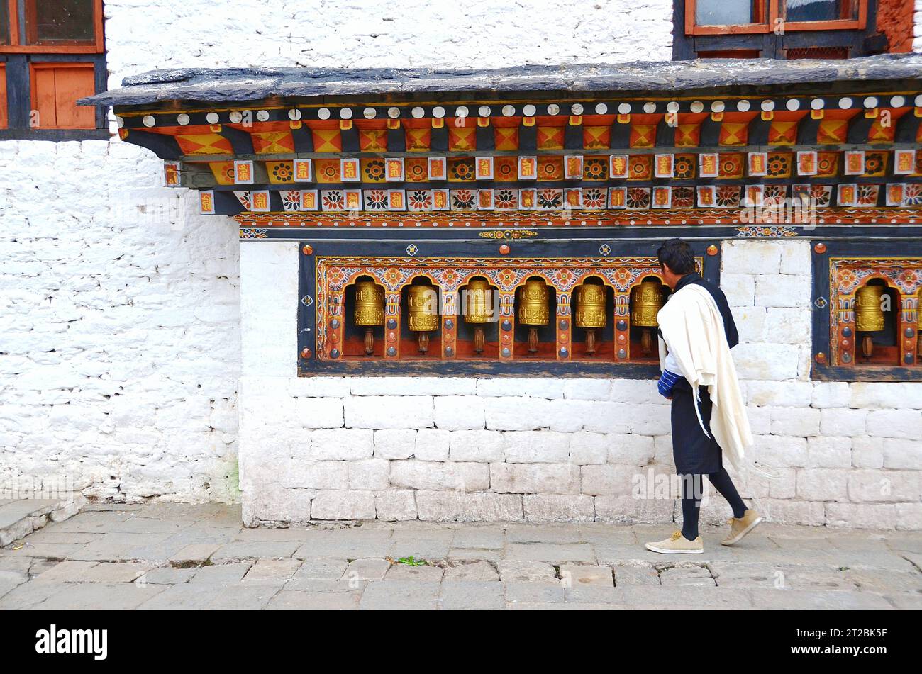 Detail view of a monastery in Bhutan with a man rotating the prayer ...