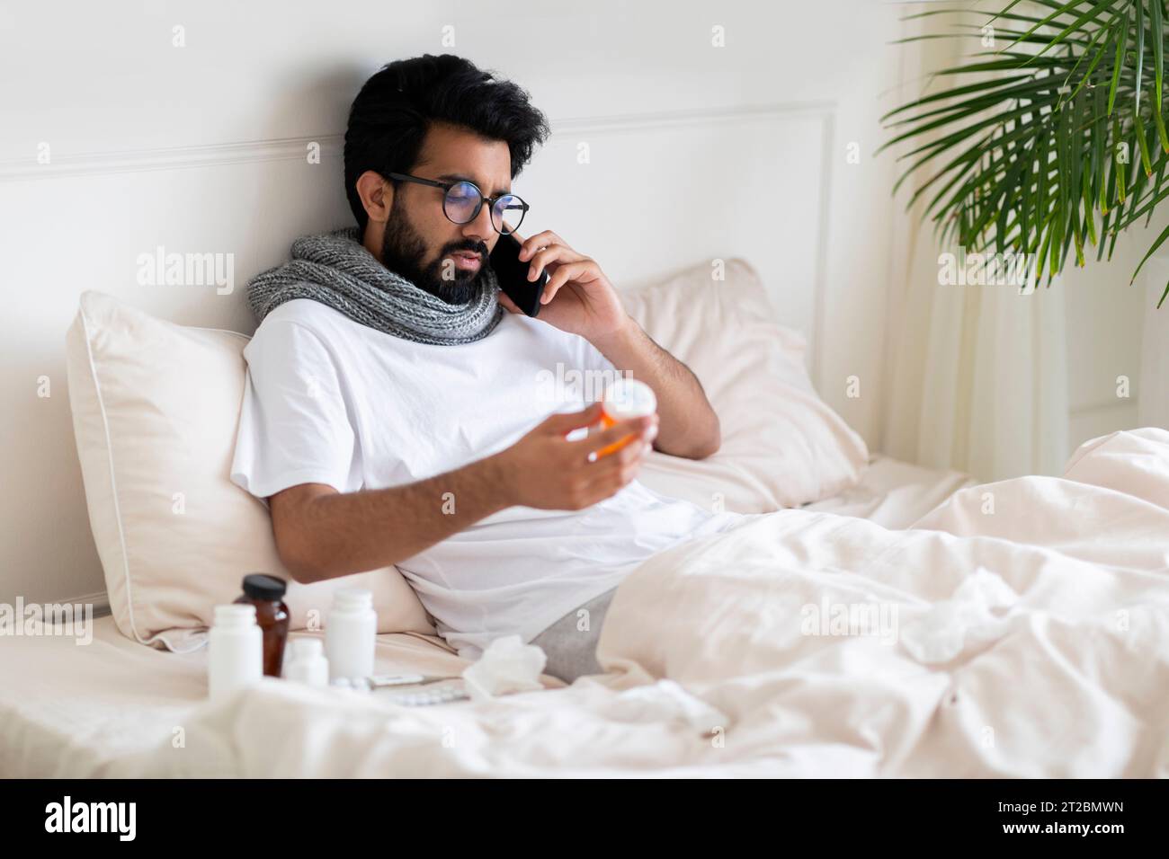 Sick Indian Man Holding Pills And Calling Doctor While Sitting In Bed ...