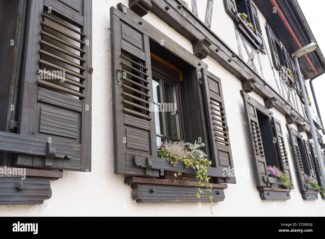 Window of a house with shutters and flowers in a German village. Close ...