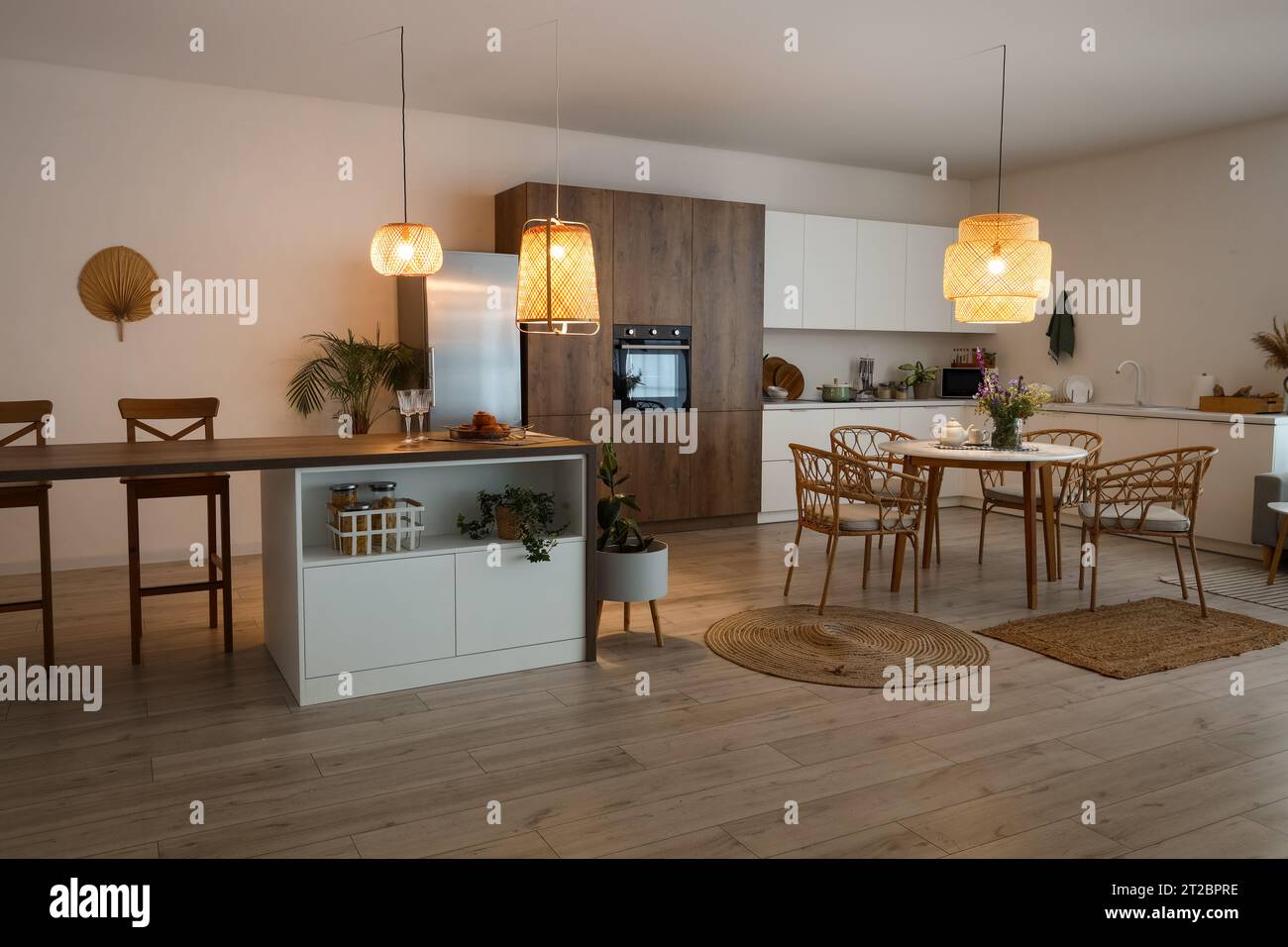 Interior of modern kitchen with dining table, island and glowing lamps ...