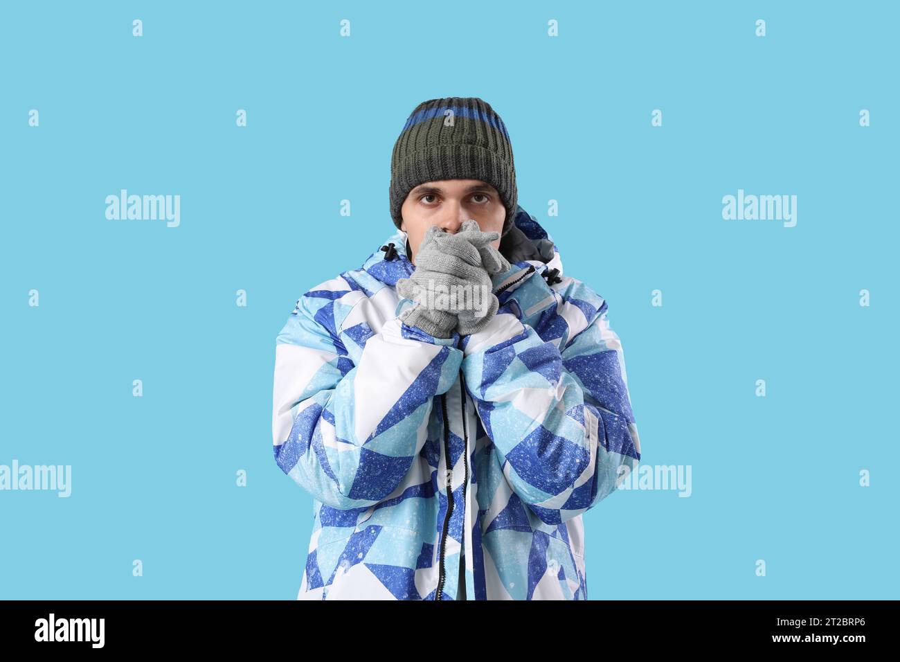 Frozen young man in winter clothes on color background Stock Photo - Alamy