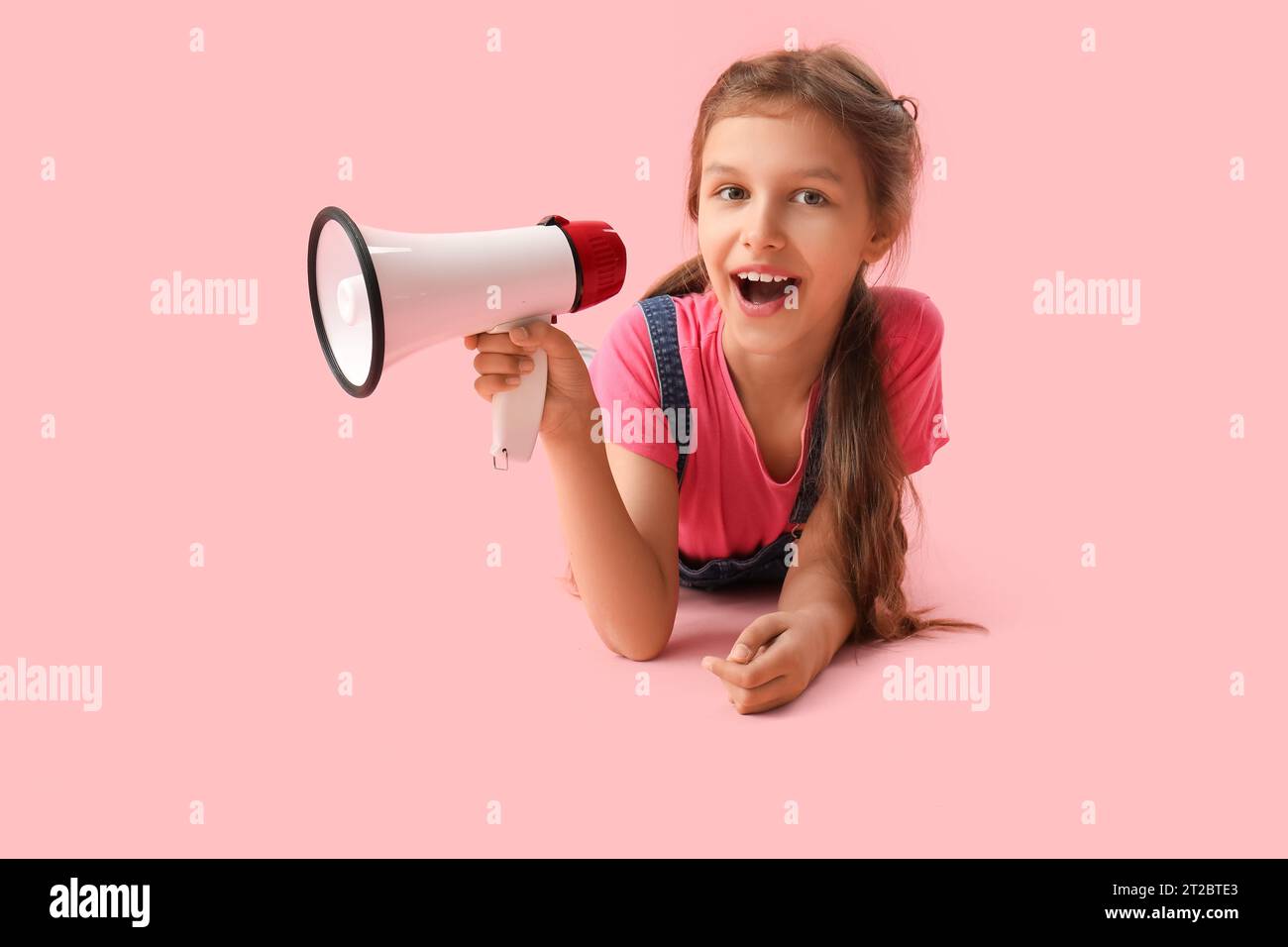 Little girl with megaphone lying on pink background Stock Photo - Alamy