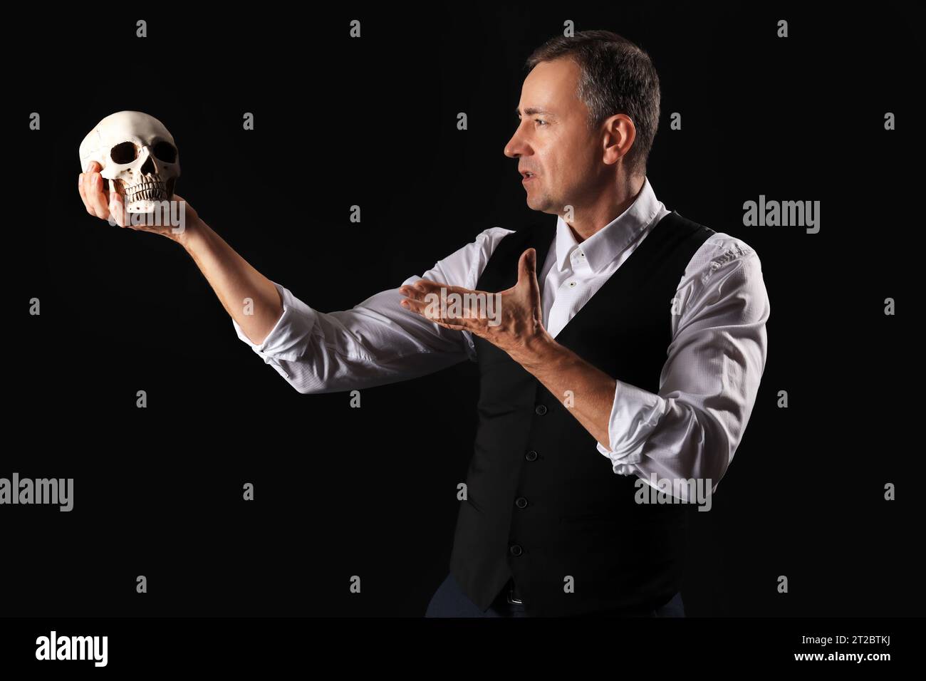 Mature actor with skull on dark background Stock Photo - Alamy