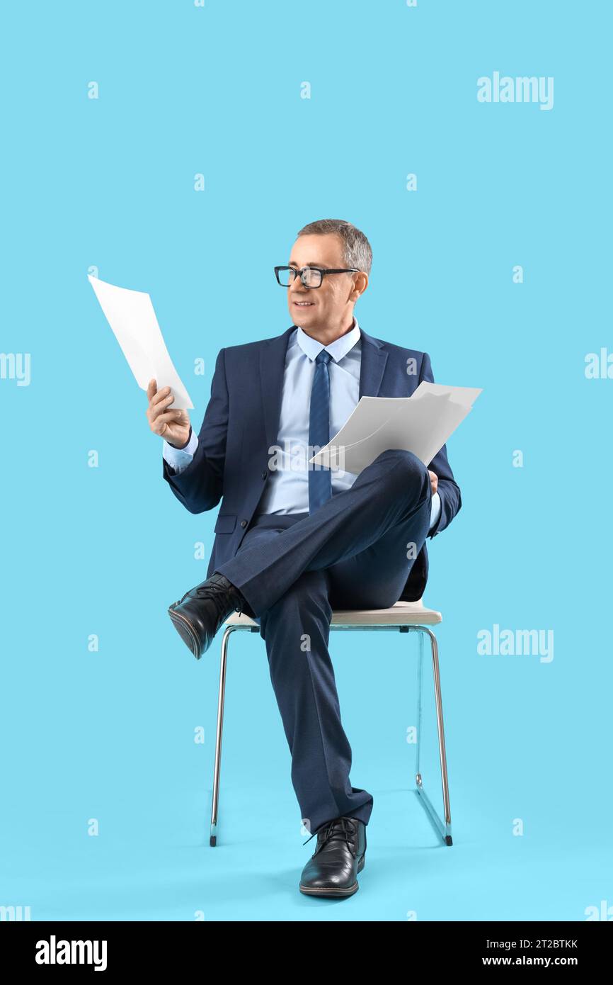 Mature actor reading film script in chair on blue background Stock ...