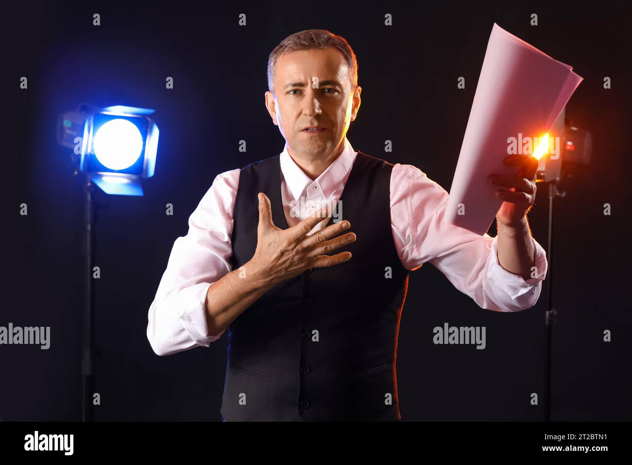 Mature actor reading film script on dark background Stock Photo - Alamy