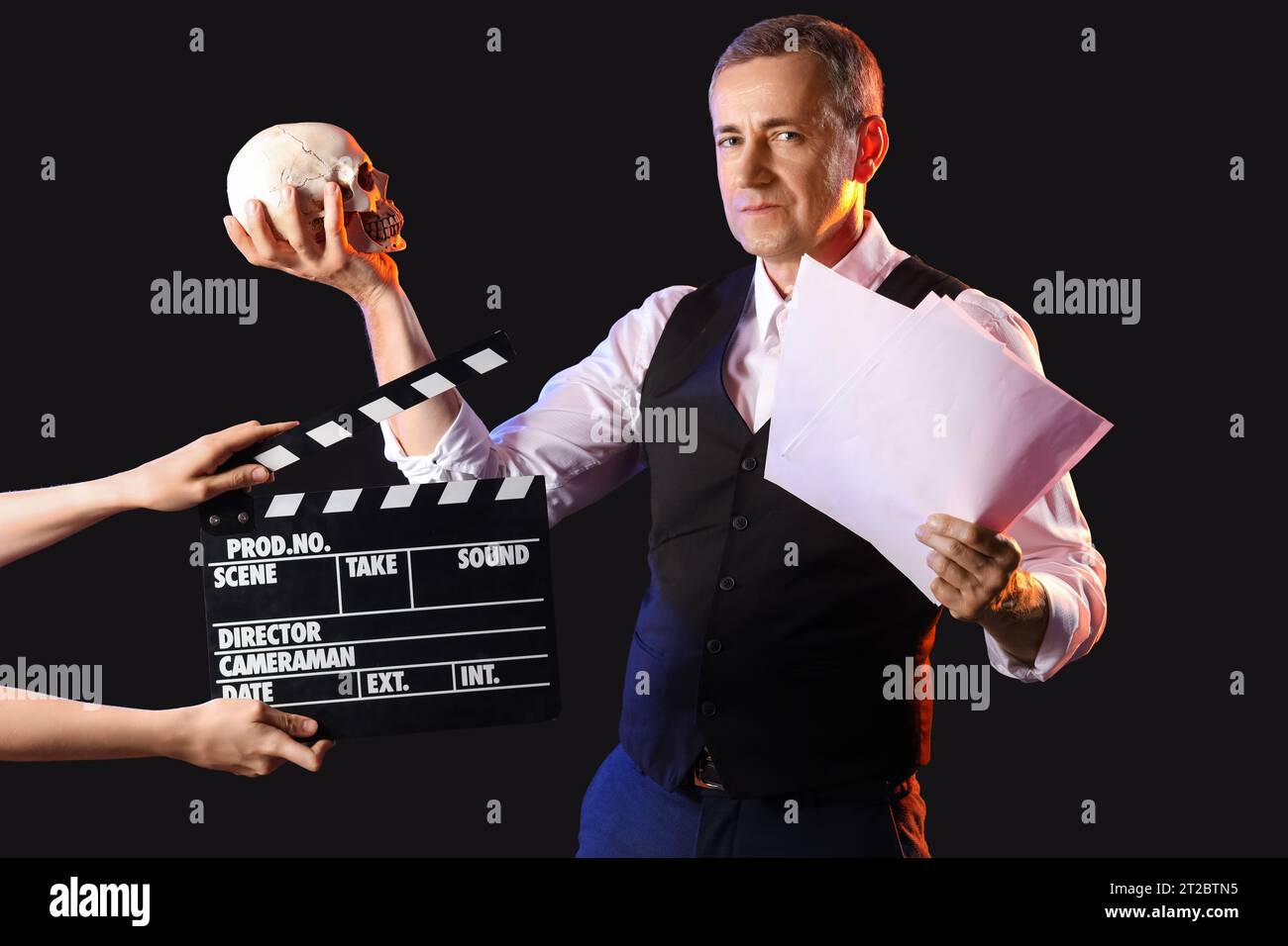 Mature actor with skull reading script on dark background Stock Photo ...