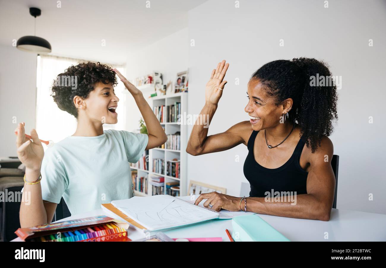 Cheerful woman helping daughter doing homework. Mother and daughter ...