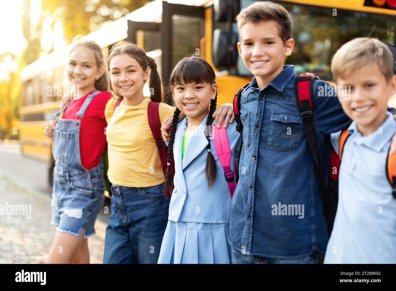 Cheerful kids ready to board school bus, standing outdoors Stock Photo ...