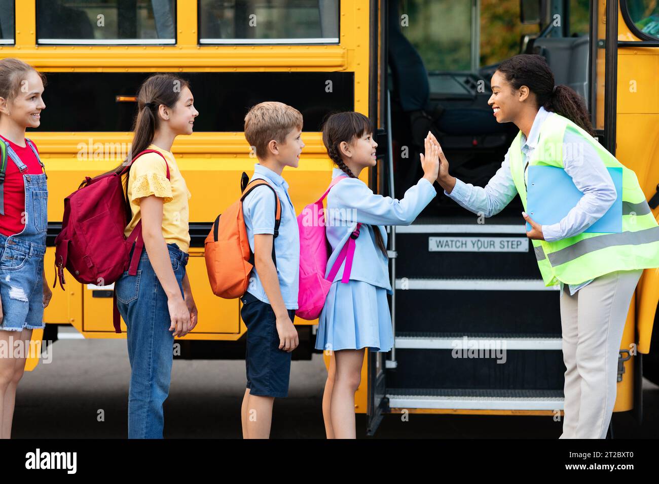 Kids boarding school bus receiving joyful high five from smiling black ...