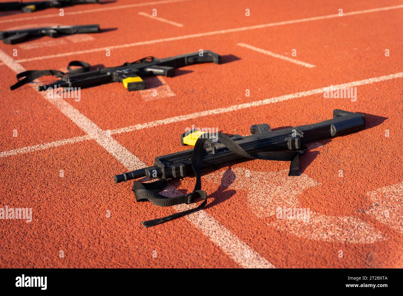 Black practice weapons on the dotted starting line of an orange running ...