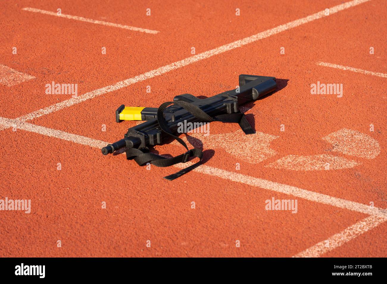 Black practice weapons on the dotted starting line of an orange running ...