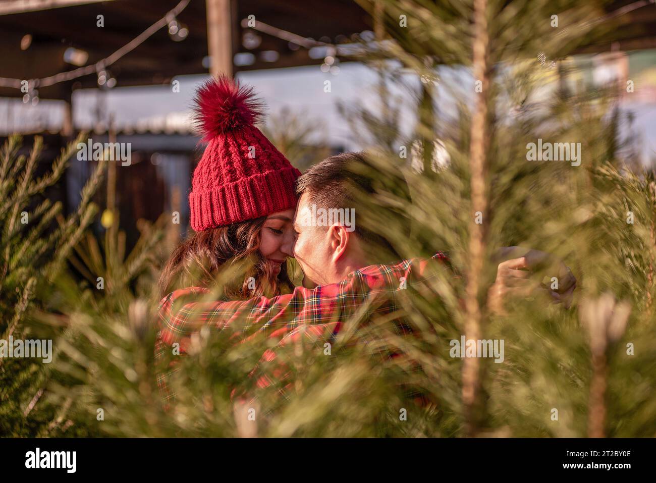 Beautiful couple in love in checkered red shirts, knitted hats hug ...