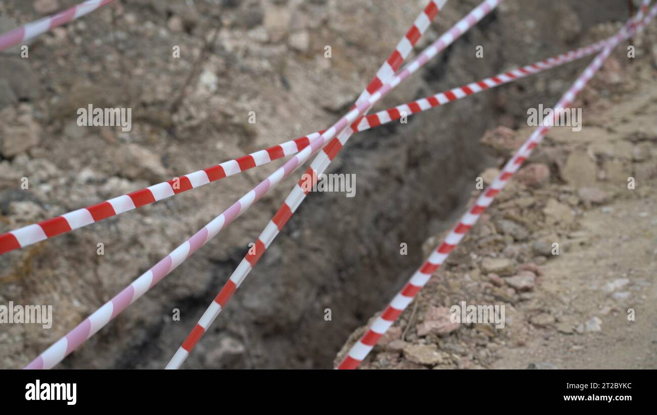 Red white barrier tape trenches. Focus on red and white barrier tape at ...