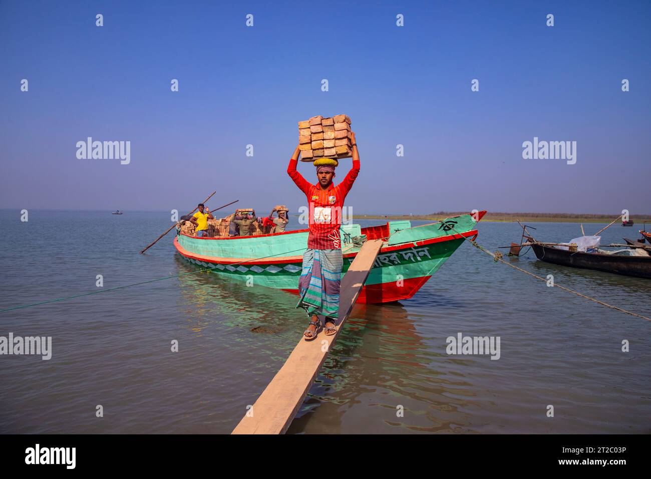 Workers unloading bricks from a boat on the bank of Meghna River in ...