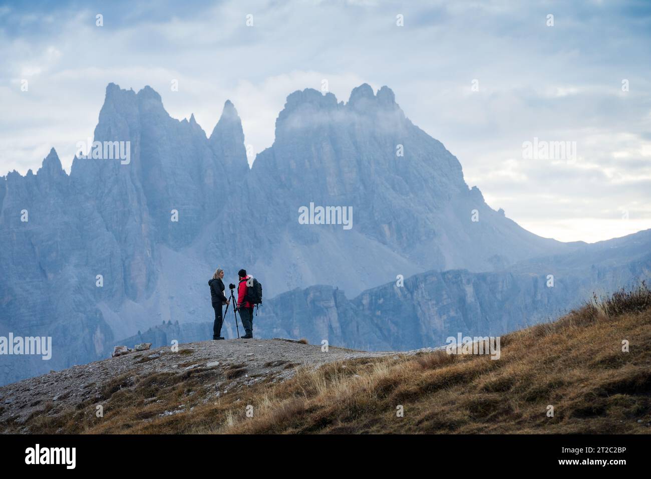 Two landscape photographers talking in front of impressive rock wall of ...