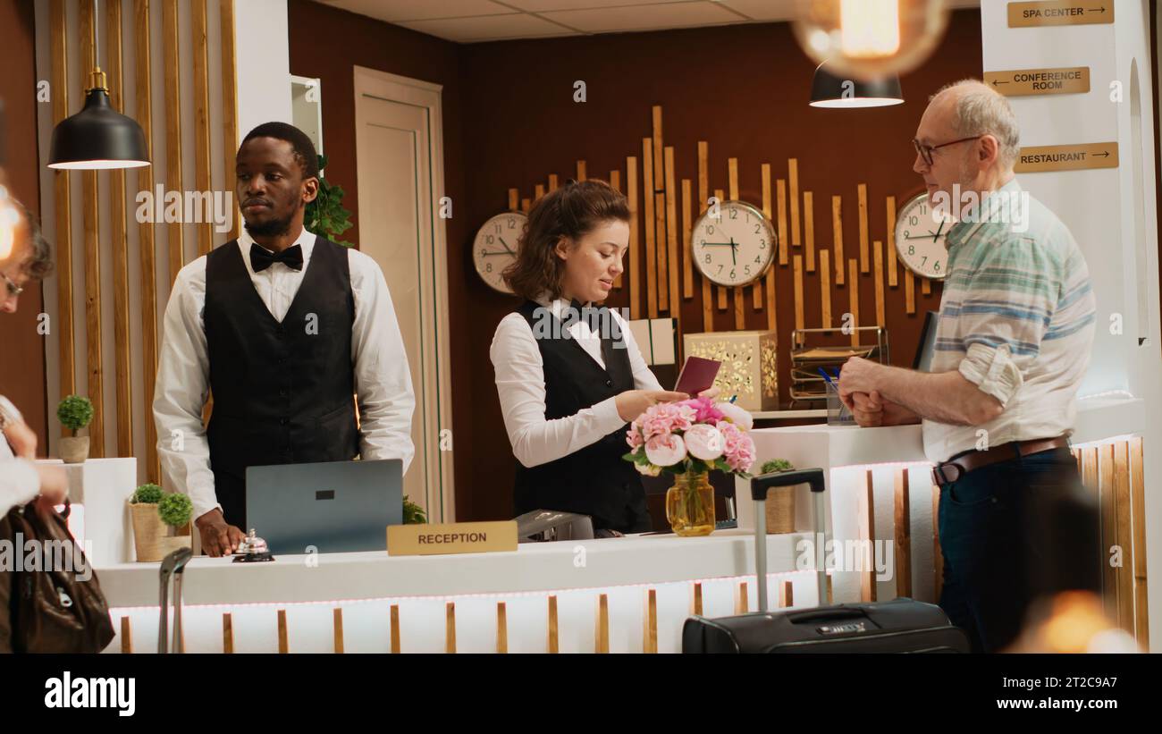 Couple offering passports for check in, hotel concierge verifying id ...