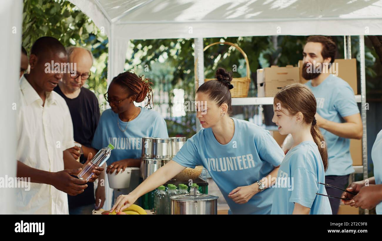At non-profit food drive, side-view of female charity workers handing ...
