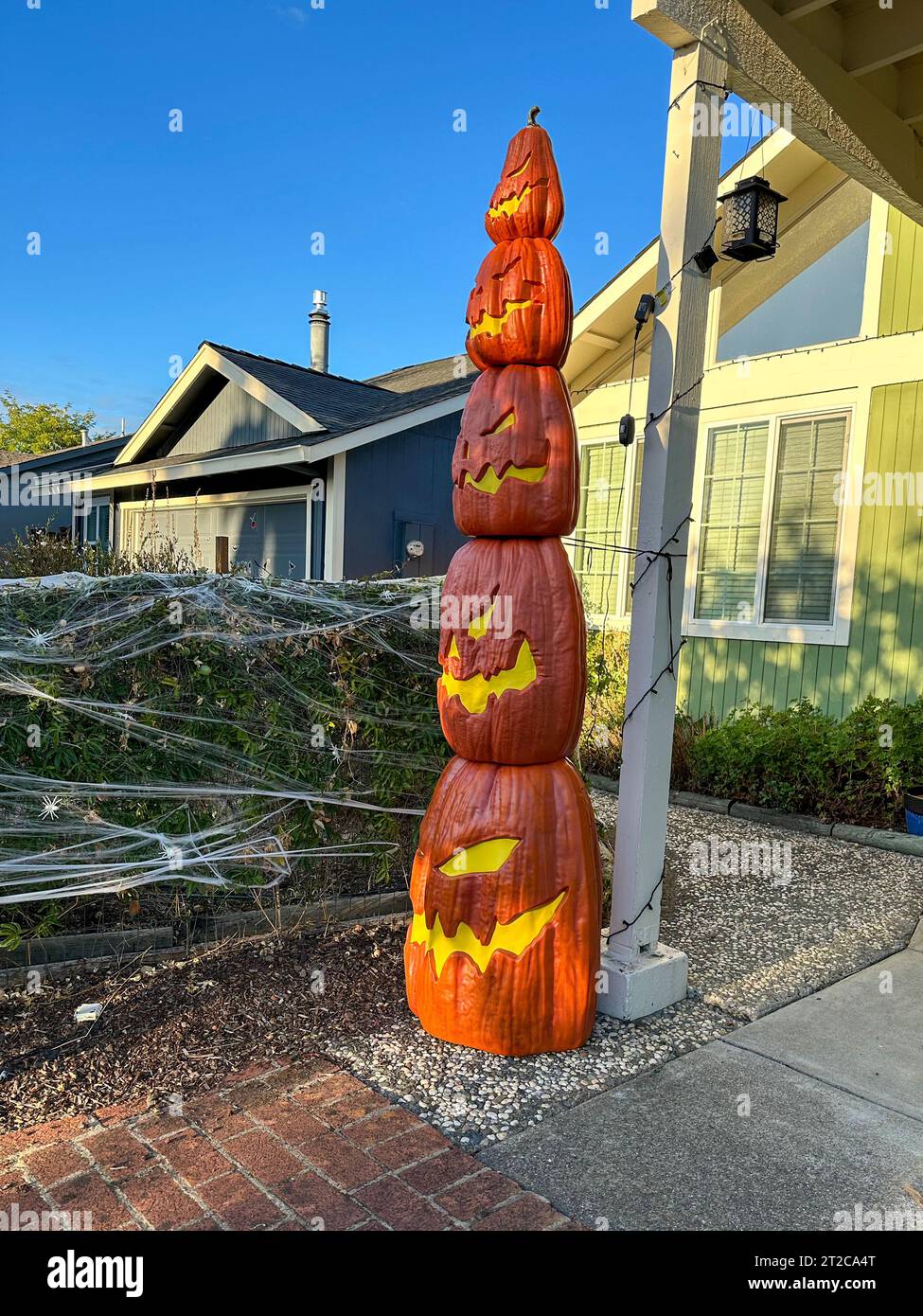 A vertical Halloween decoration of five orange pumpkins piled on top of ...