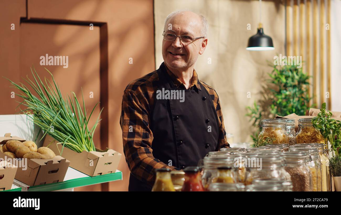 Portrait of smiling old zero waste supermarket owner using decomposable ...