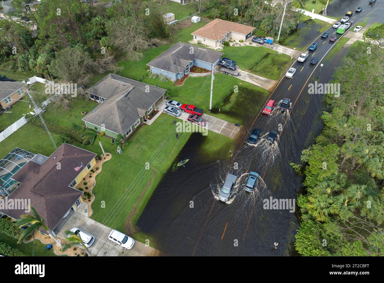 Hurricane flooded street with moving cars and surrounded with water ...
