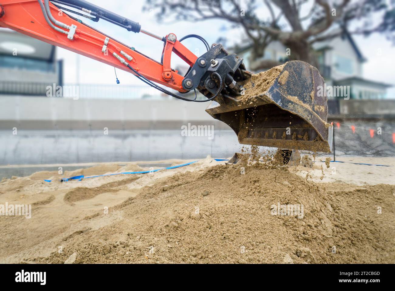 Bulldozer digging sand on a sandy beach. Beach Houses and concrete ...
