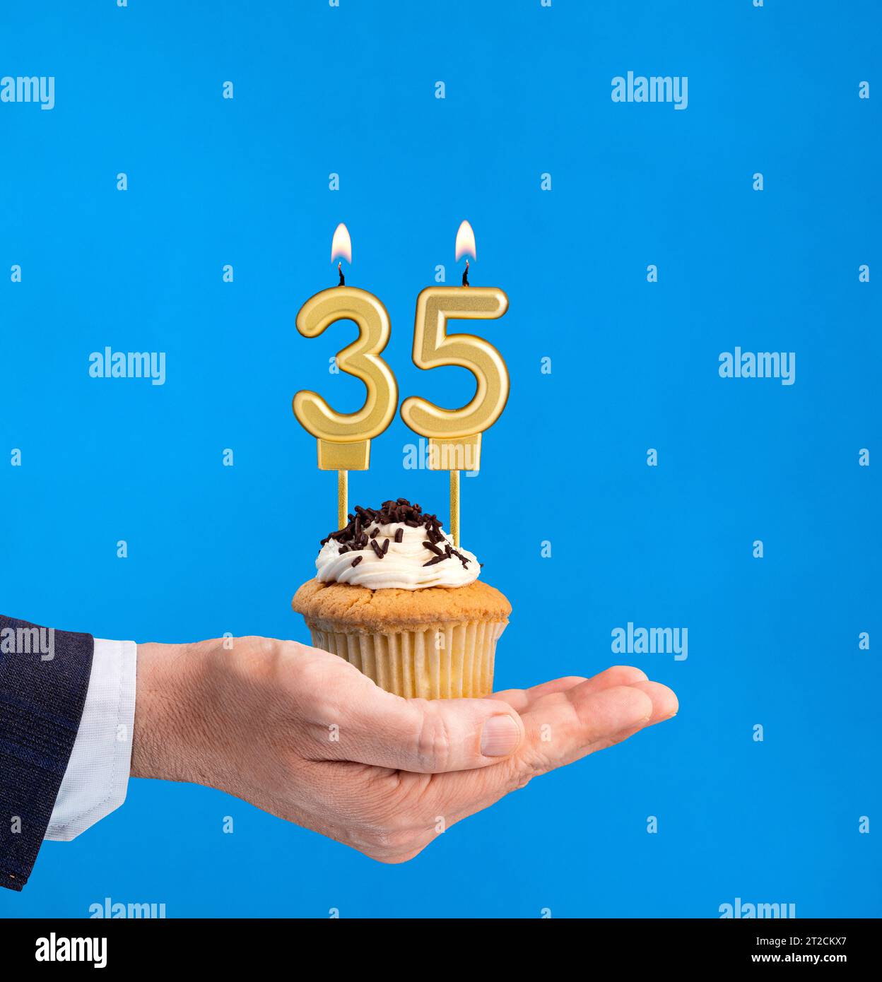 Hand holding a cupcake with the number 35 candle - Birthday on blue ...