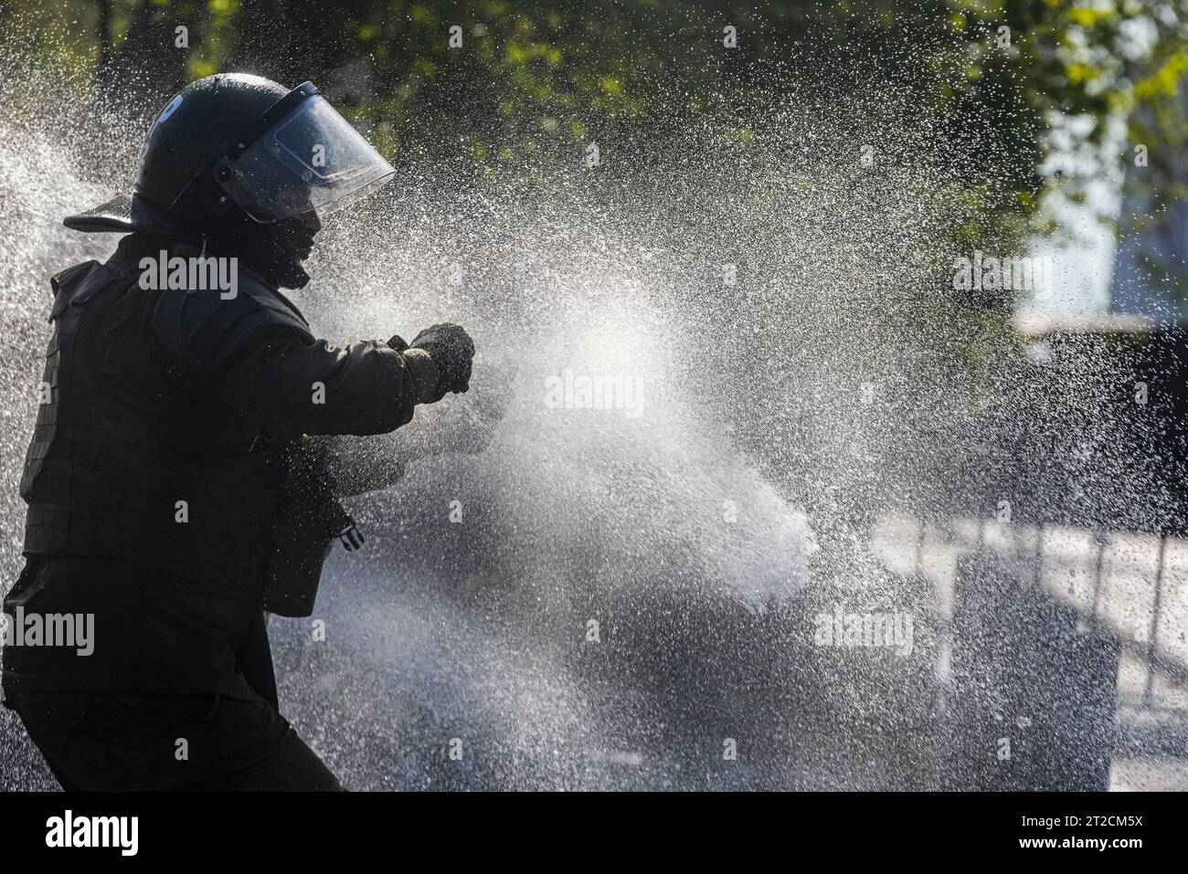 A police officer is splashed with water from a police water cannon as ...