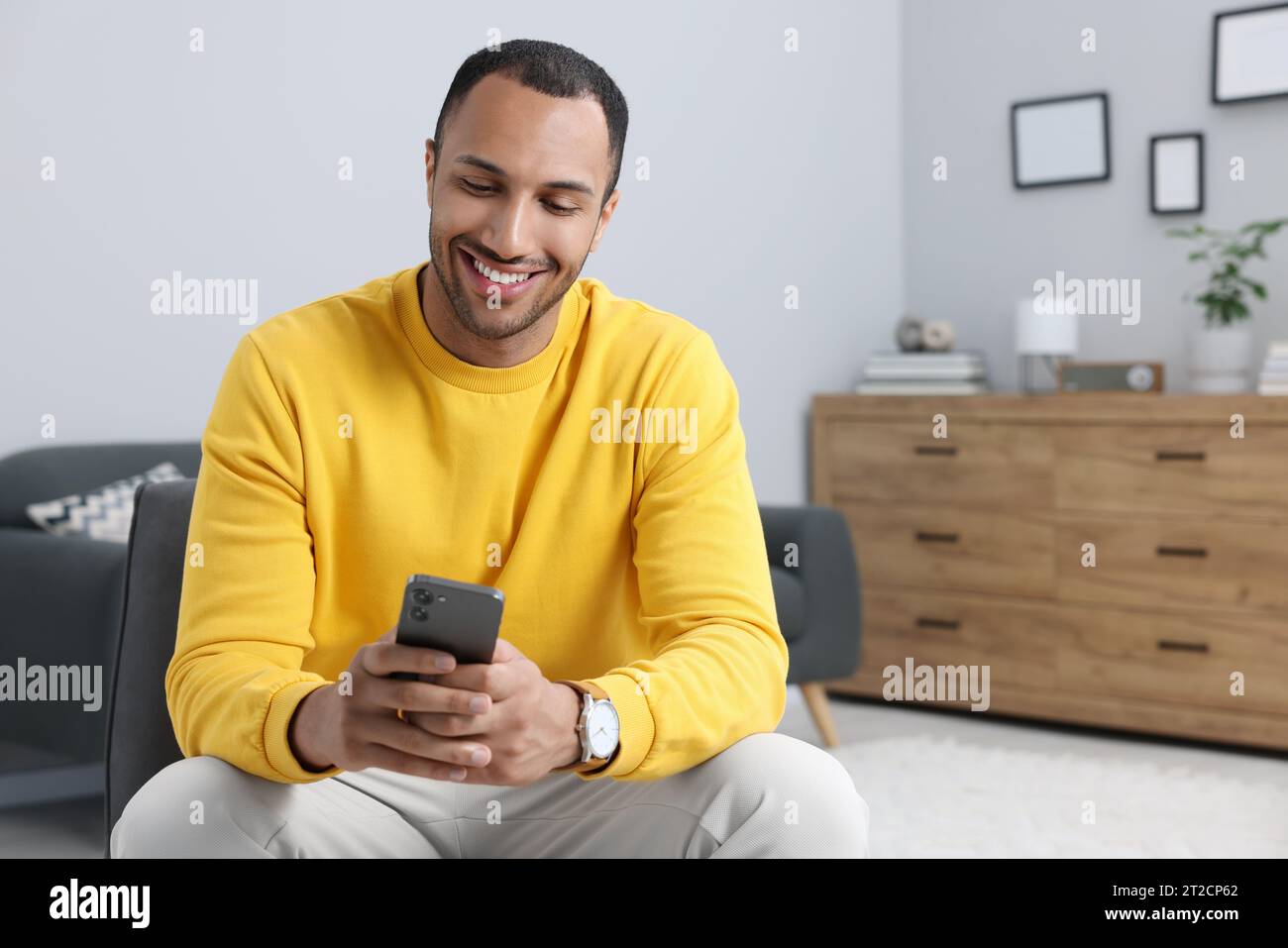 Happy man sending message via smartphone indoors Stock Photo - Alamy