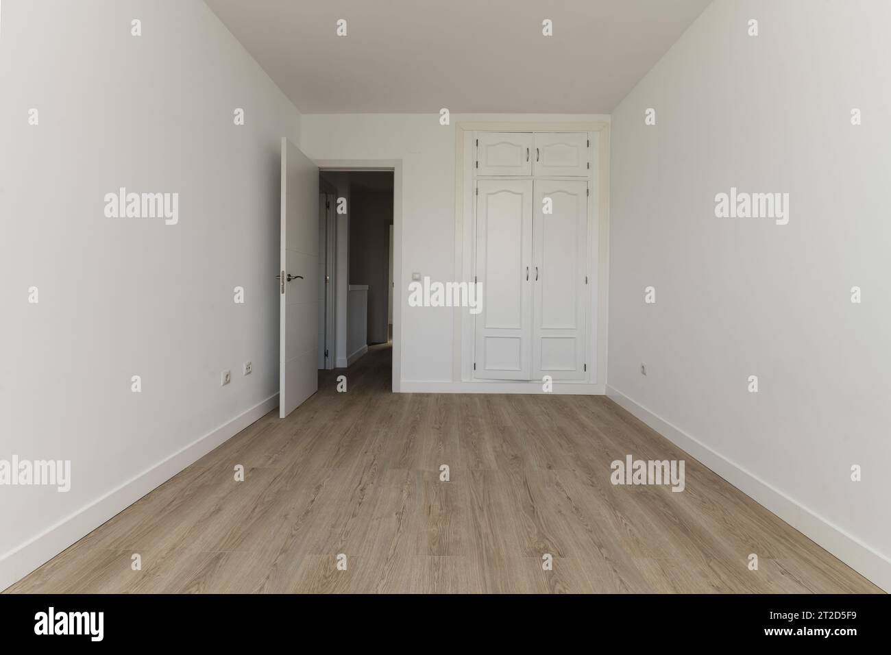 Empty bedroom with a built-in wardrobe with two white wooden doors ...
