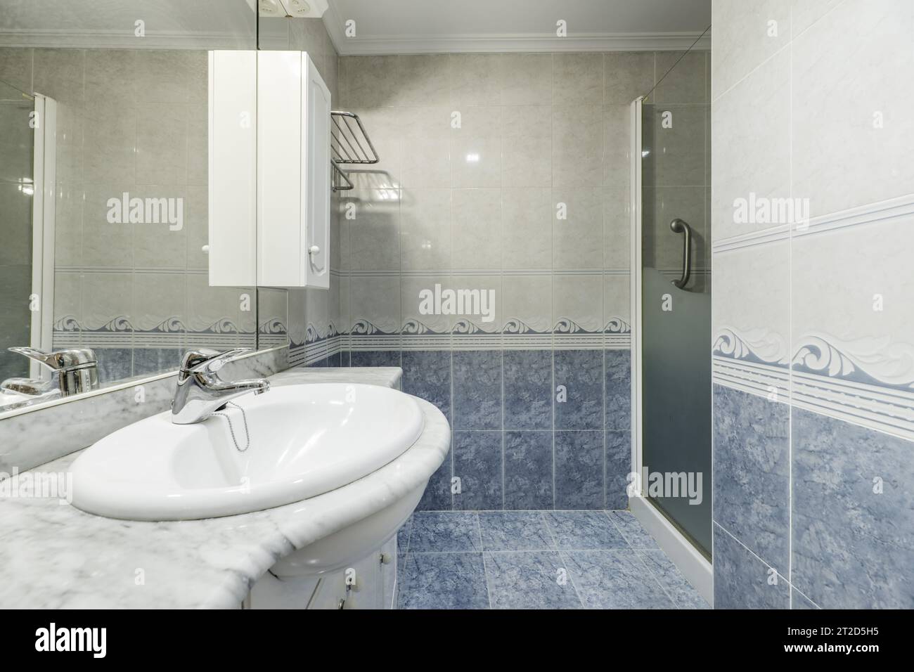 Bathroom of a home with two-color tiles divided by a marine border, a ...