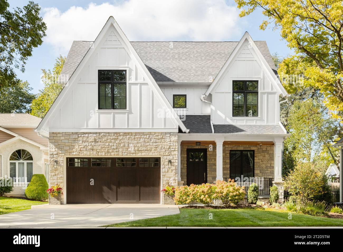 A new, white modern farmhouse with a grey shingled roof and black ...
