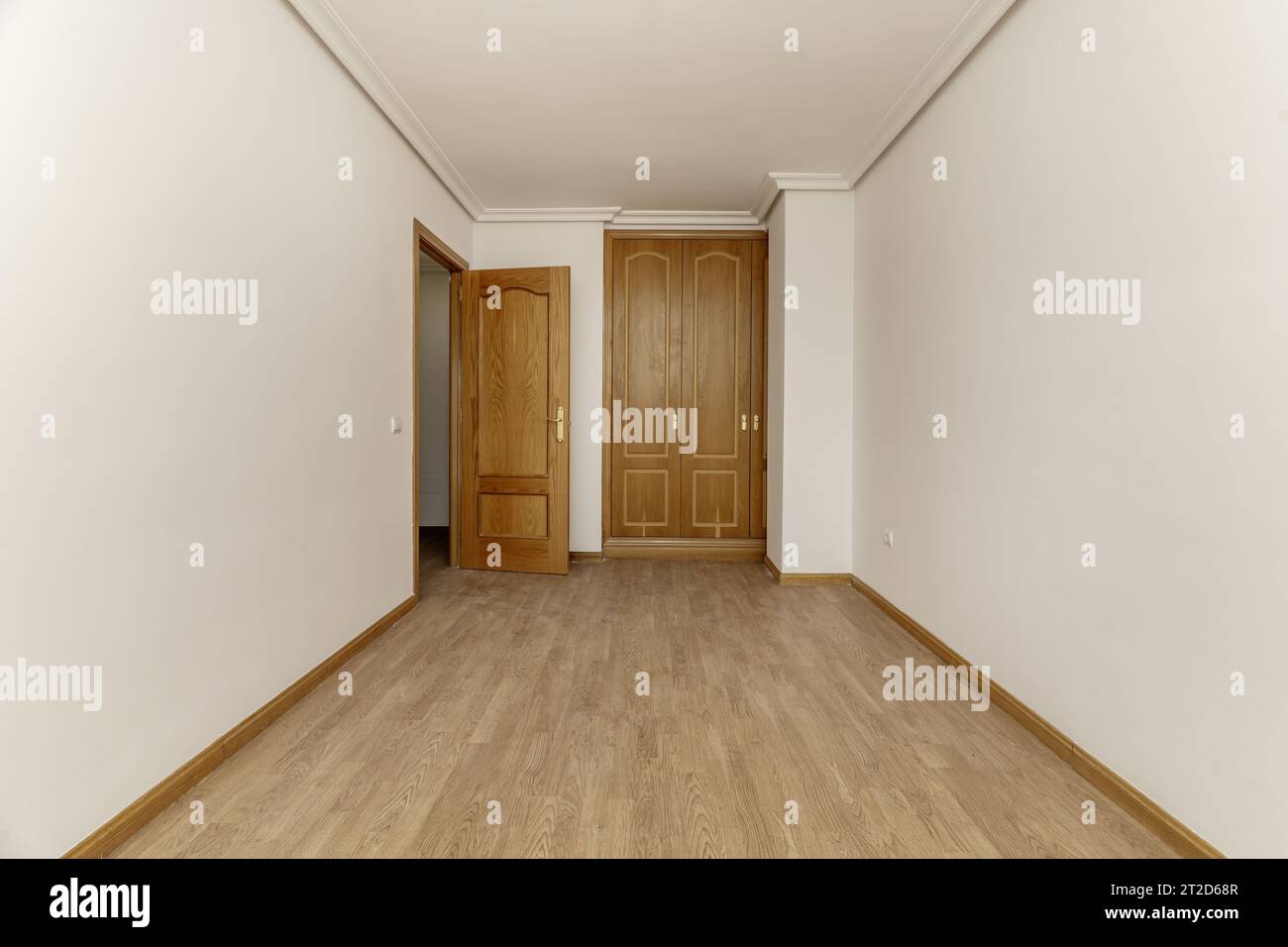 Empty bedroom with a built-in wardrobe with two oak wood doors with ...