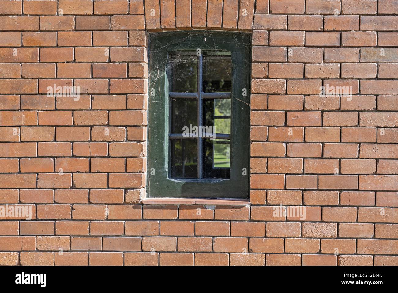 a small window with metal bars and cobwebs on a clay brick wall Stock ...