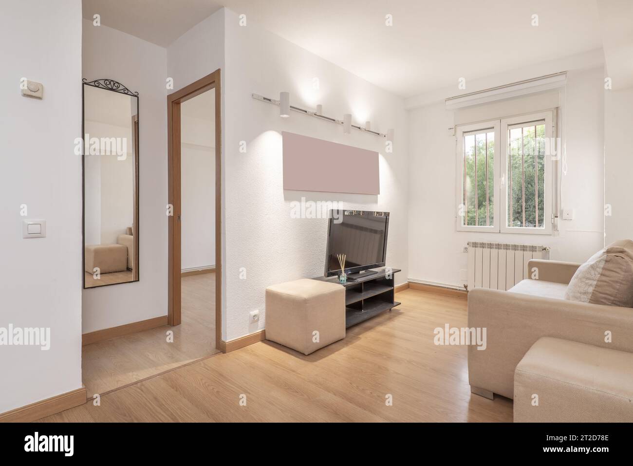 Small living room of a house with beige fabric sofa, barred window ...