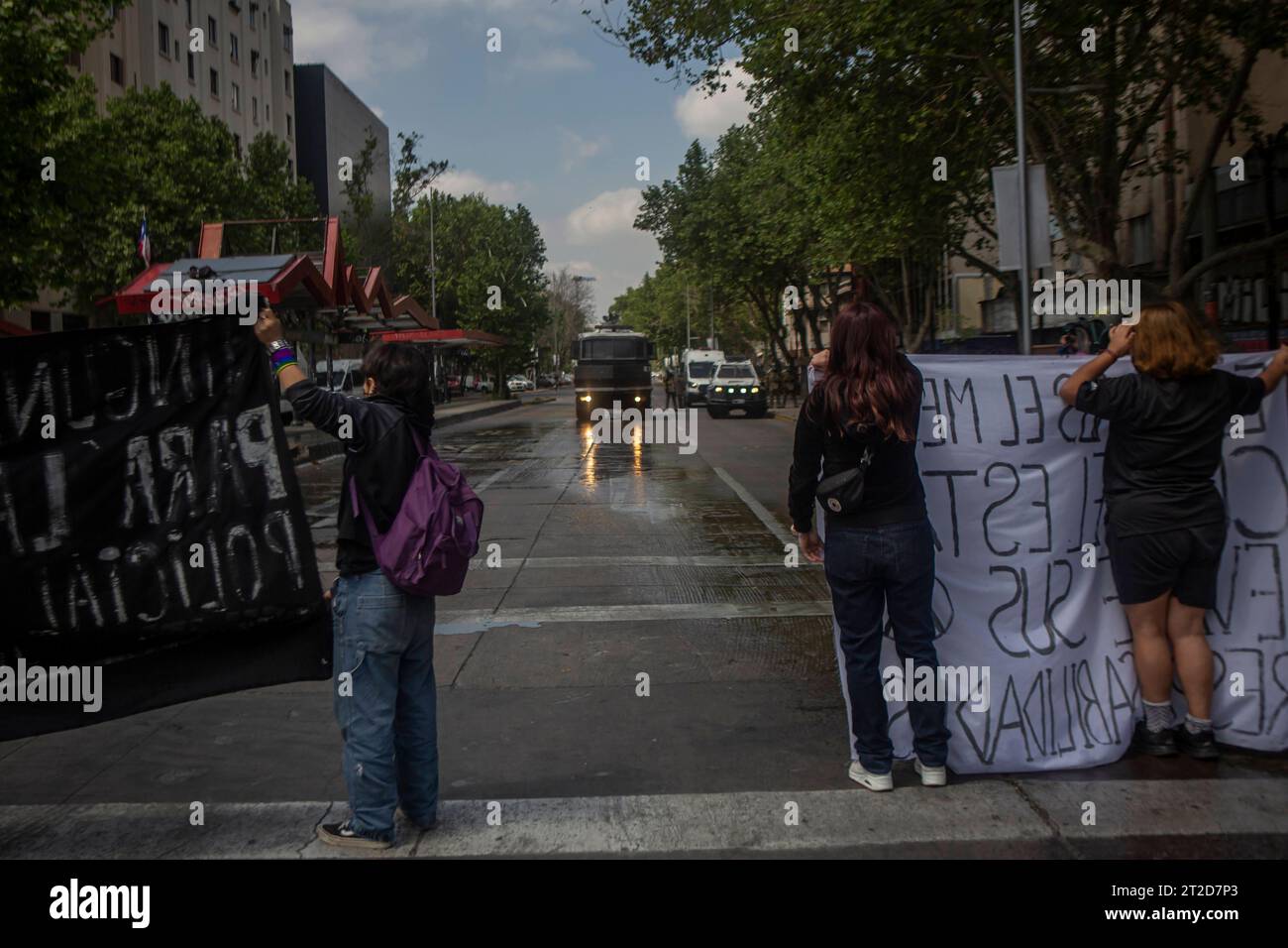 Persons holds banners in front of a police water car, during the 4th ...